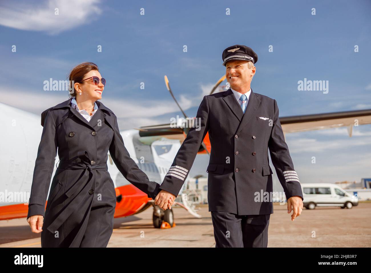 Joyful male pilot and his wife waking hand in hand at airport Stock ...
