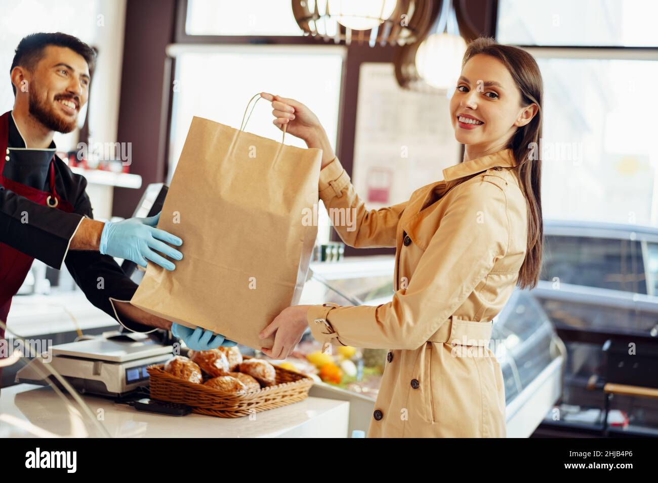 Shop assistant handling shopping bag to female customer in grocery ...