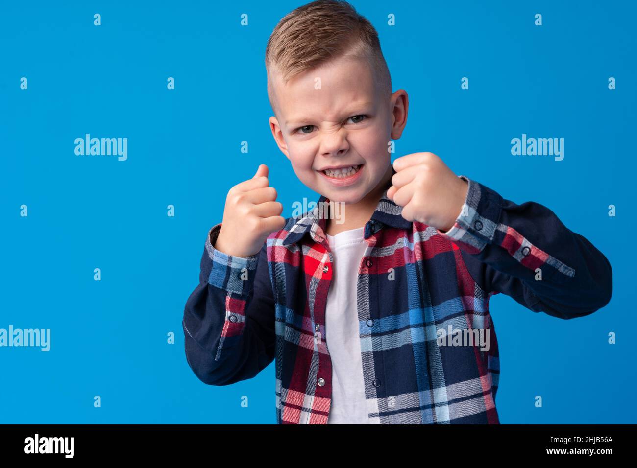 Portrait of angry little boy on blue background Stock Photo - Alamy