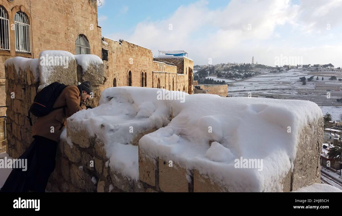 An Israeli man takes a photo as he stands atop the Old City walls ...