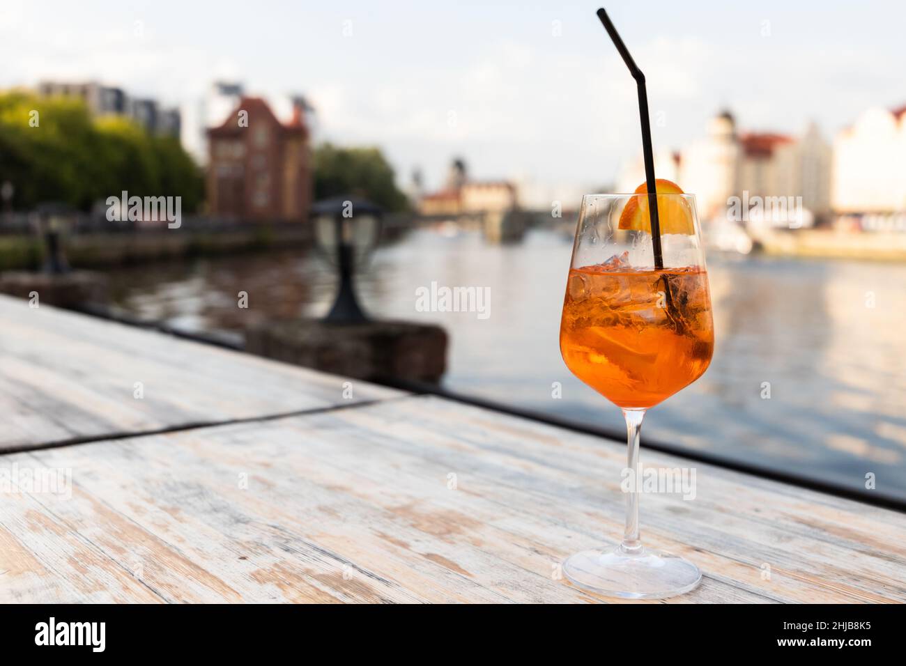 Glass of orange cocktail stands on a table of an outdoor bar terrace ...