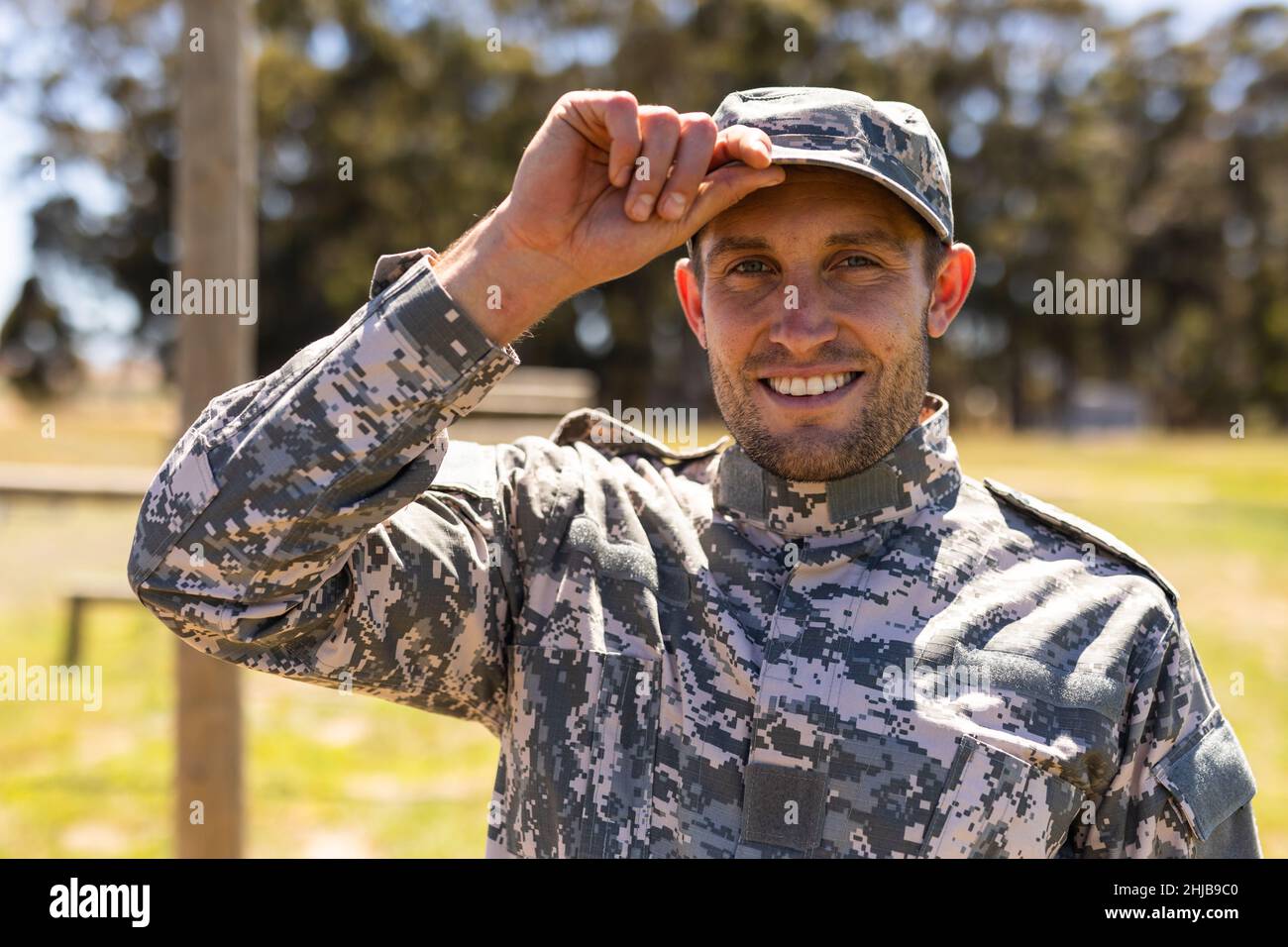 Portrait of caucasian soldier in uniform holding his cap and smiling at ...