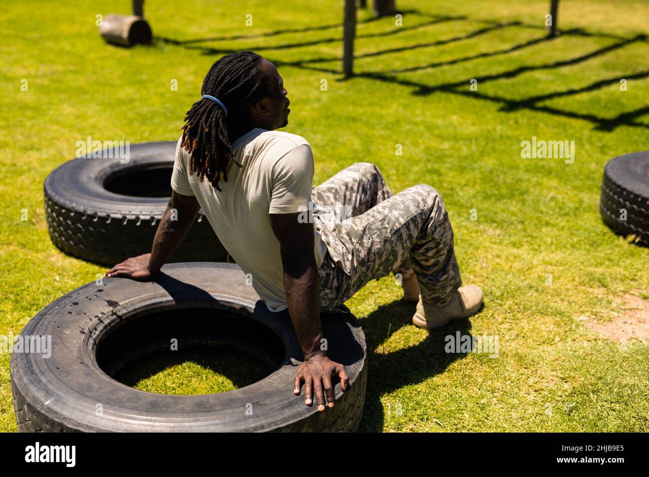 Tired african american male soldier sitting on the tire at boot camp ...
