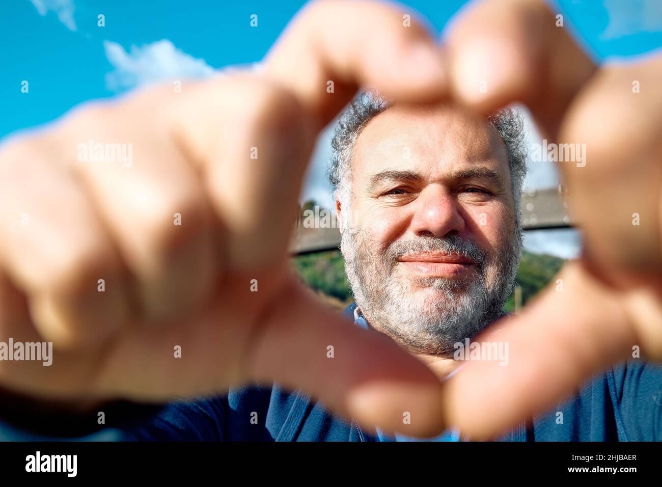 Close up portrait of happy sincere middle aged bearded man making heart ...