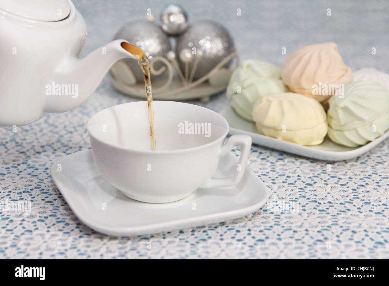 Tea party time. Hostess pours tea into cups from the kettle, in a piece ...