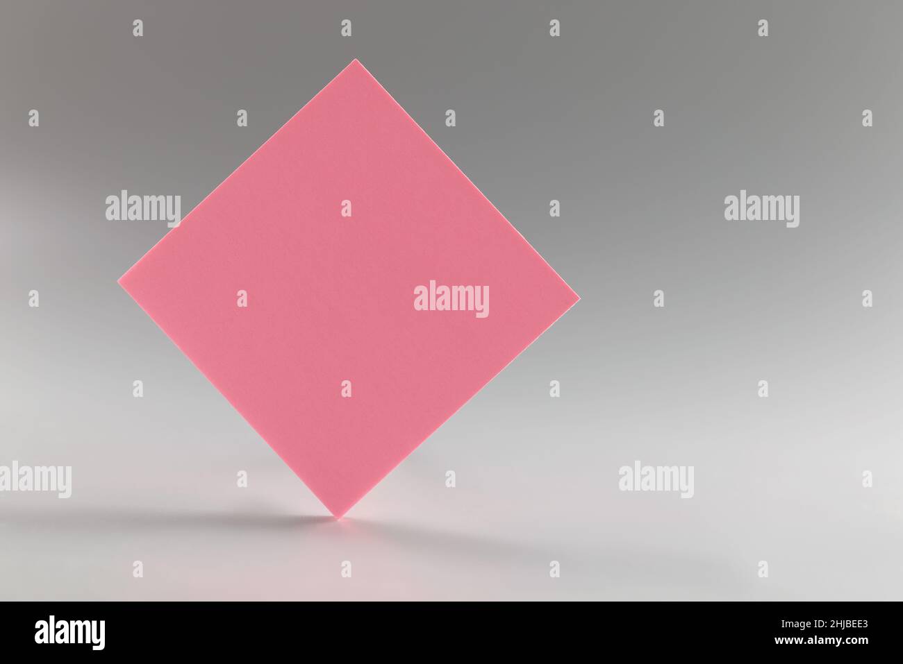 Pink sticker standing on sharp edge on grey background Stock Photo - Alamy