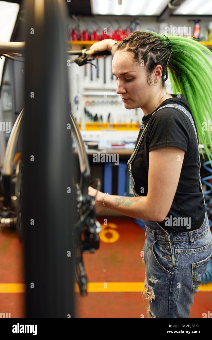 Side view of woman with long bright dreadlocks inspecting broken ...