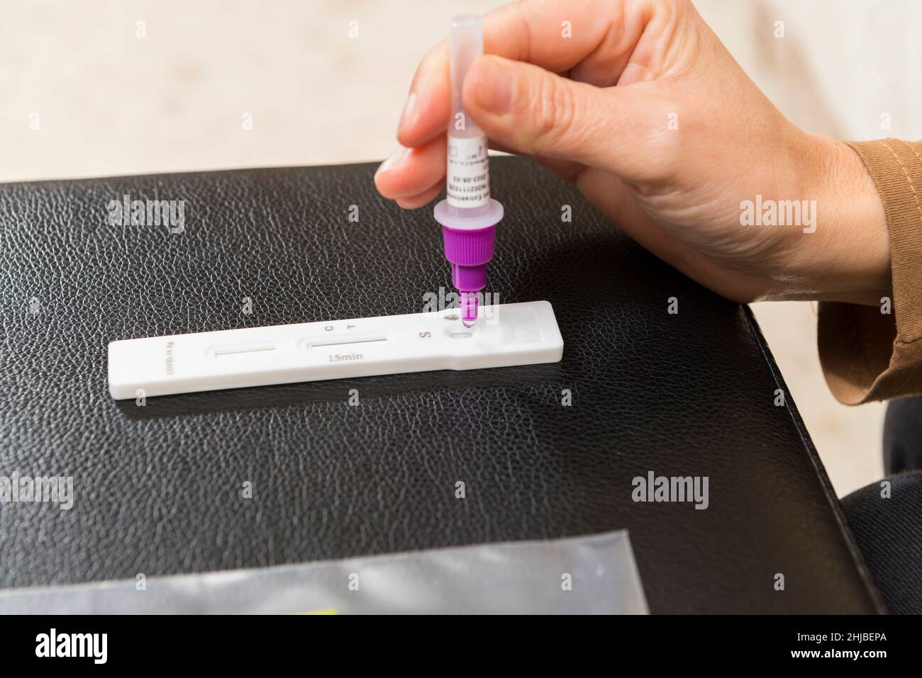 Detail of a woman's hands placing a drop from the sampling tube on the ...