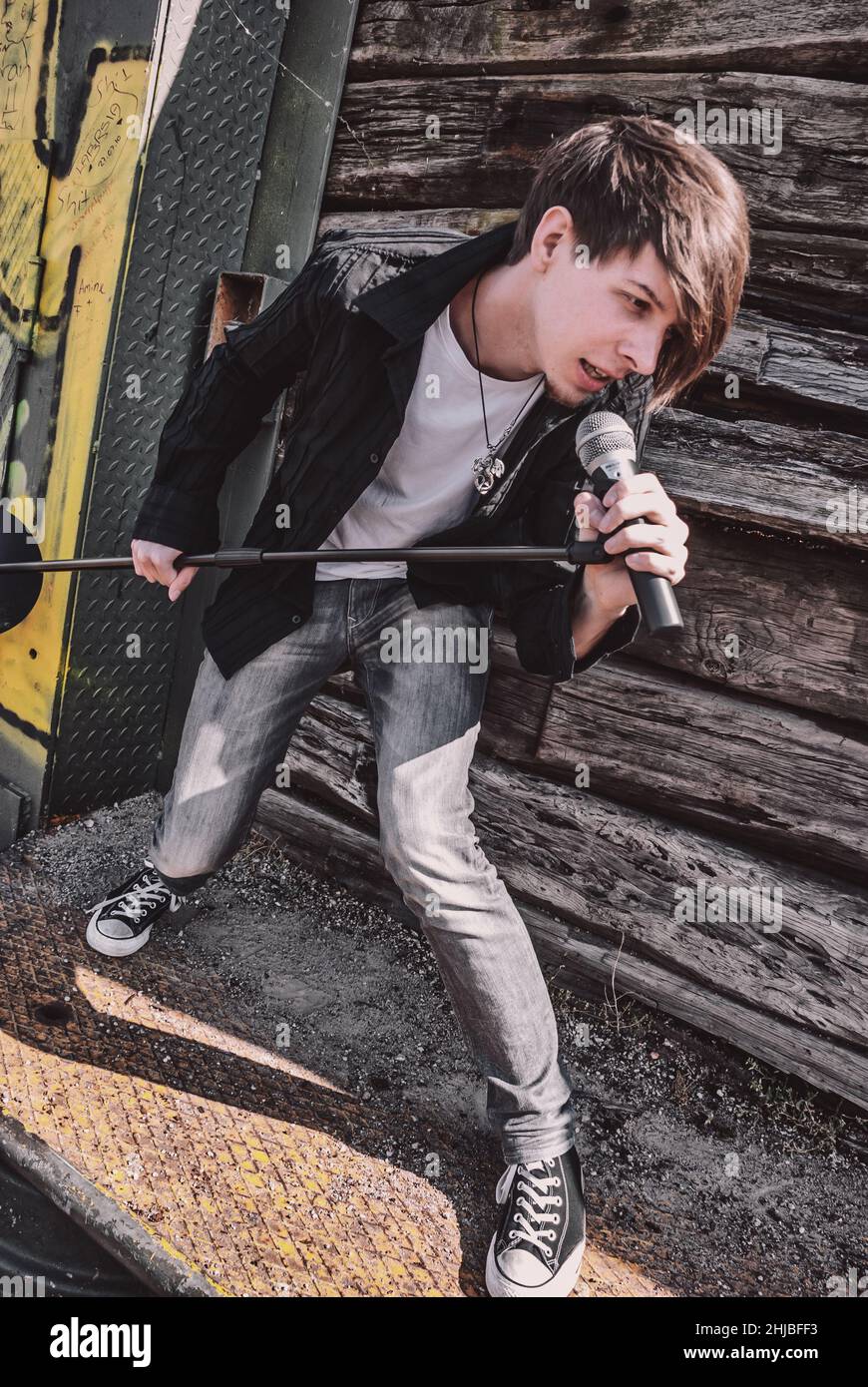 Young adult singer, with brown long hair and beard performing, rock ...