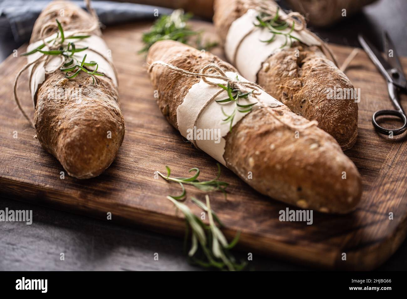 Crusty long uncut breads placed on a slicing wooden board Stock Photo ...