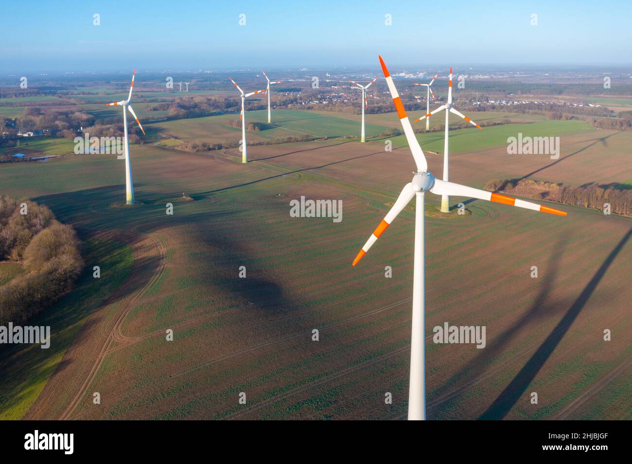 White wind turbines rotate in the wind under blue sky and are ...
