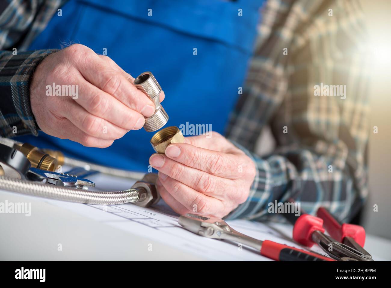 Plumber hands using plumbing fittings, light effect Stock Photo - Alamy
