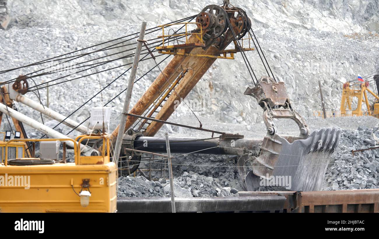 Excavator and railway with ore. Excavator fills with ore rail cars in ...