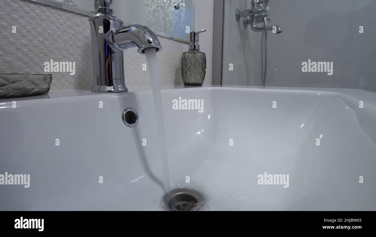 Open chrome faucet washbasin. Water flows from the tap in the modern ...