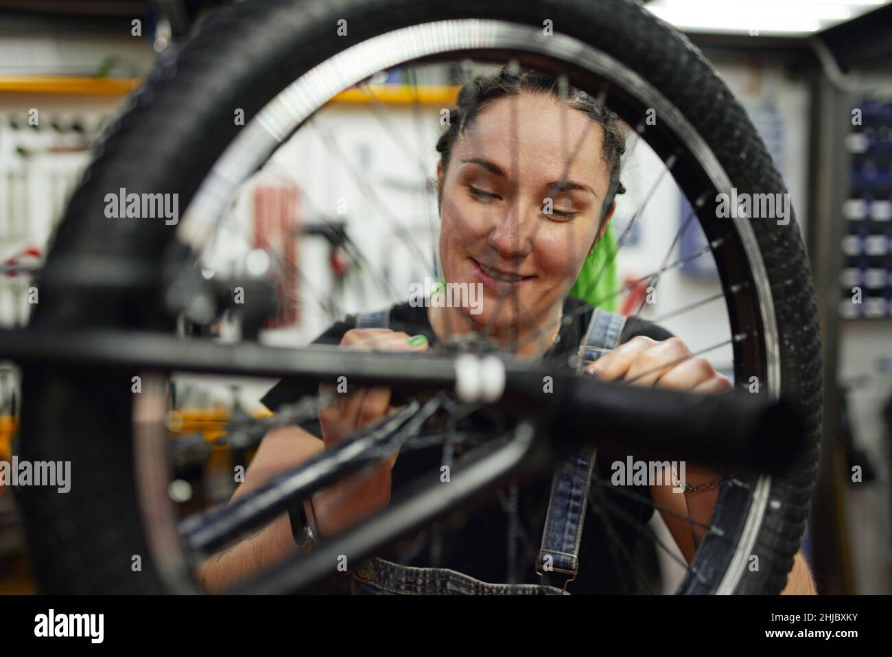 Cheerful female technician using instrument and fixing wheel of ...