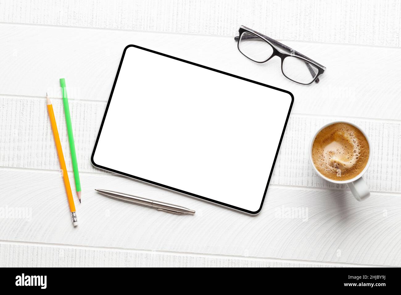 Tablet with blank screen on desk, coffee cup and office supplies. Top ...