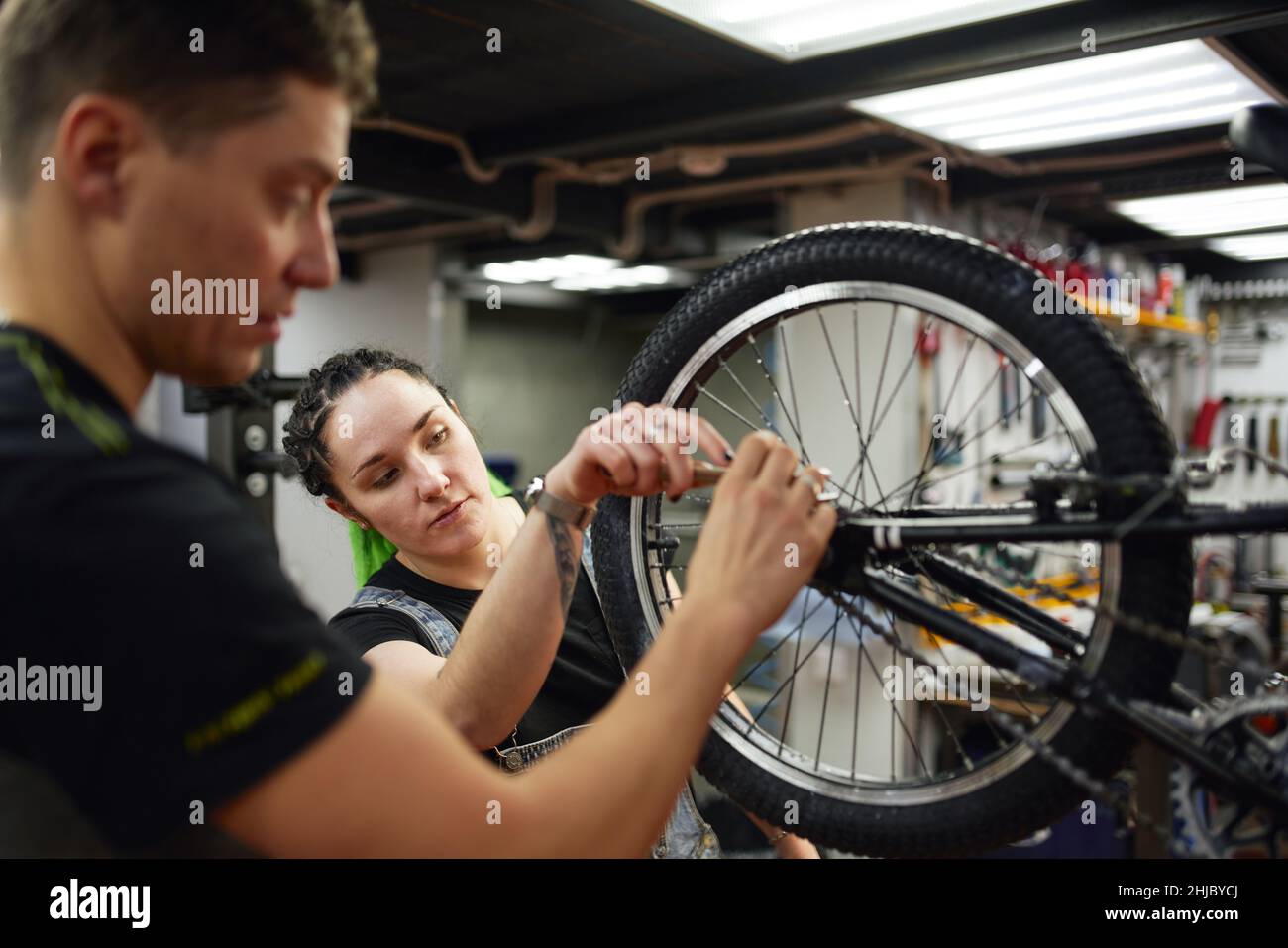 Focused male and female technicians fixing wheel of modern bicycle ...