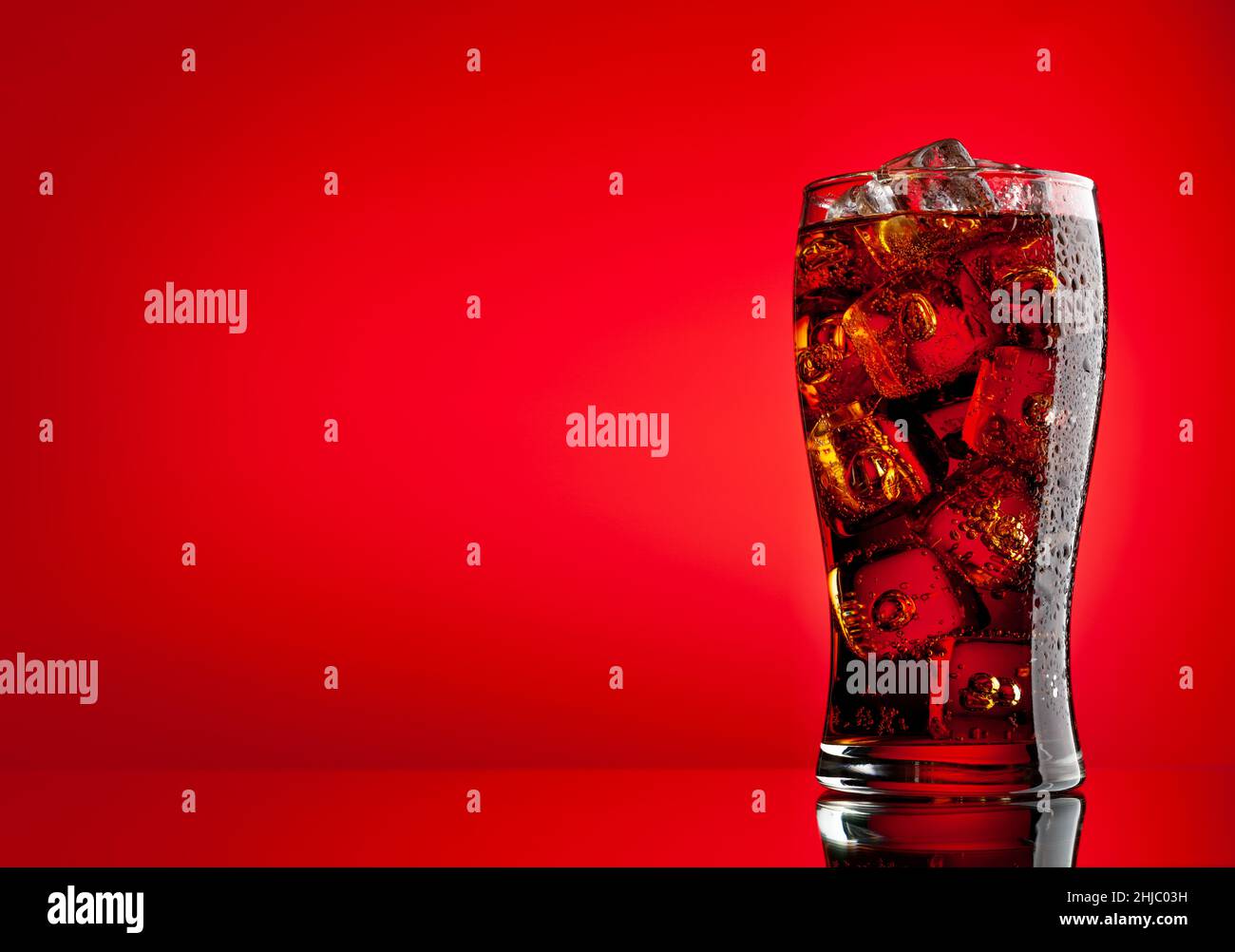 Cola with ice. Fresh cold sweet drink with ice cubes. Over red ...