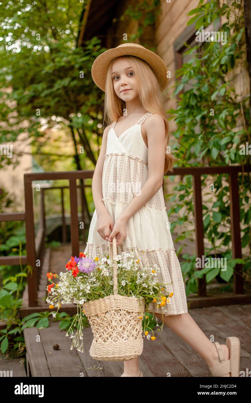 Dreamy tween girl with wildflower in basket standing on doorstep of ...