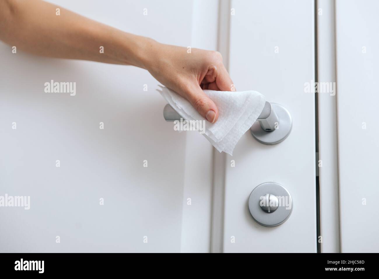 Cleaning door handles with an antiseptic wet wipe and gloves. Woman ...