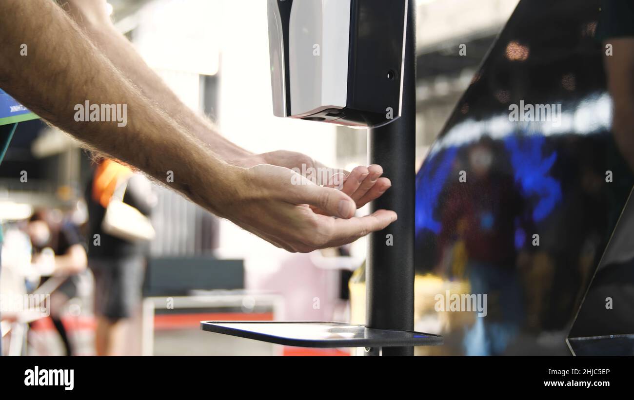 Close up of washing hands with an automatic alcohol sanitizer dispenser ...