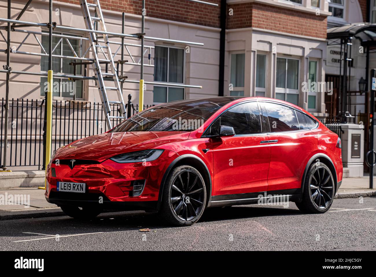 Red modern Tesla car parked at roadside in urban city by house Stock ...