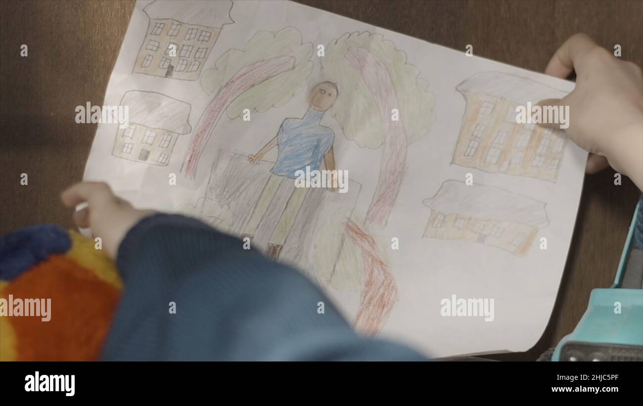 Kid puts the picture on the shelf back view. Child hangs the picture on ...
