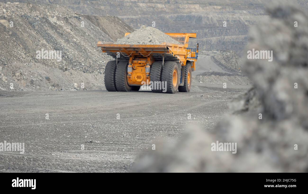 Close-up of dump truck moving on a quarry road loaded with ore. Back ...
