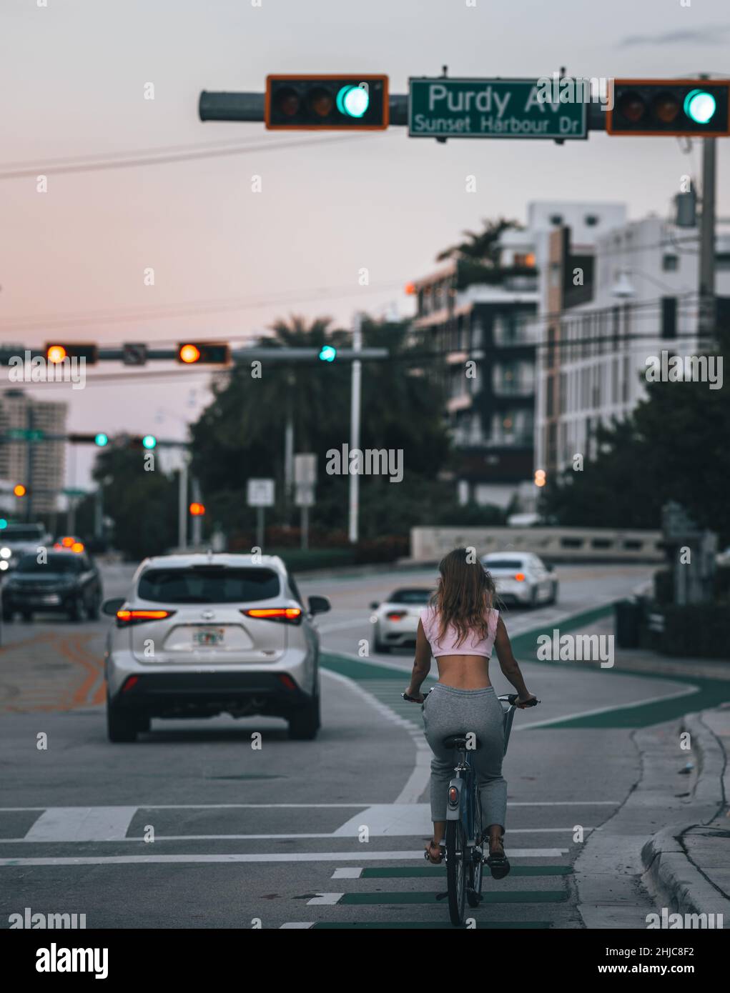 Vertical back view of female cycling near the cars in the street in the ...
