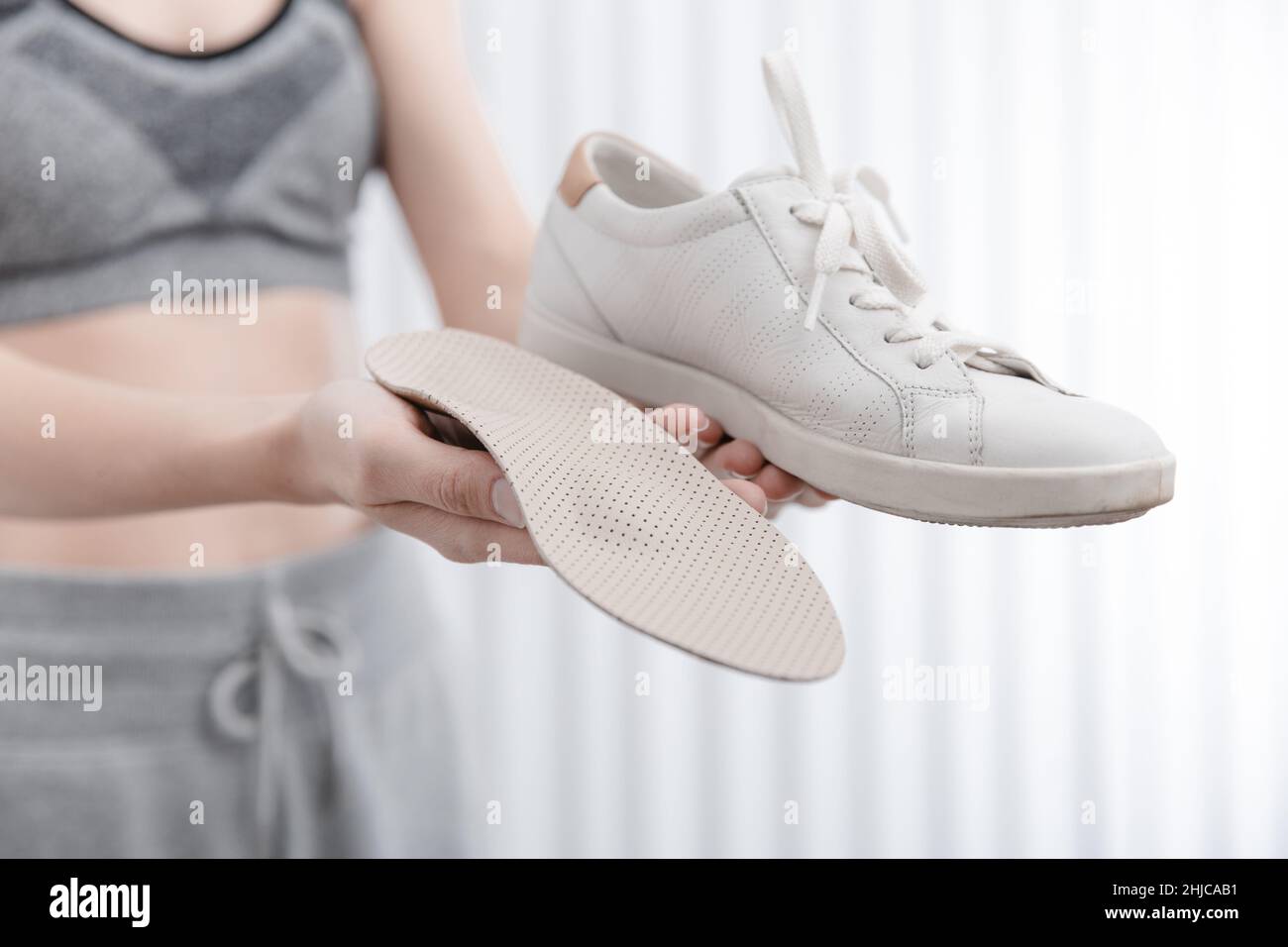 Woman putting orthopedic insole into shoe at home. Sports girl fitting ...