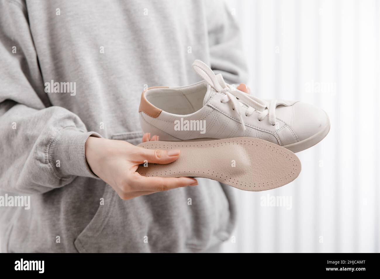 Woman putting orthopedic insole into shoe at home. Sports girl fitting ...