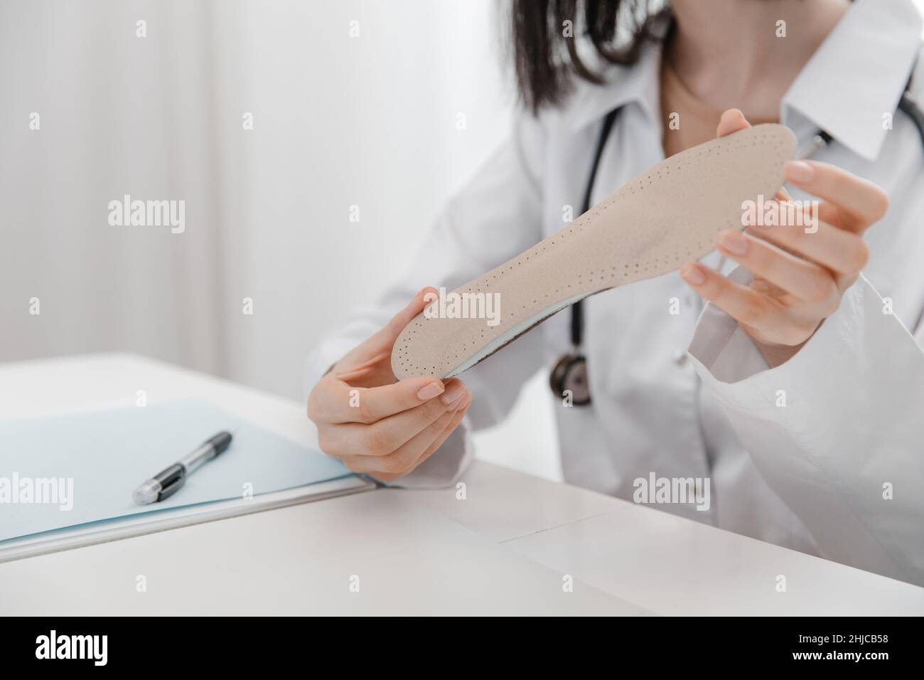Doctor holding an insole while sitting at a table. Orthopedist tests ...