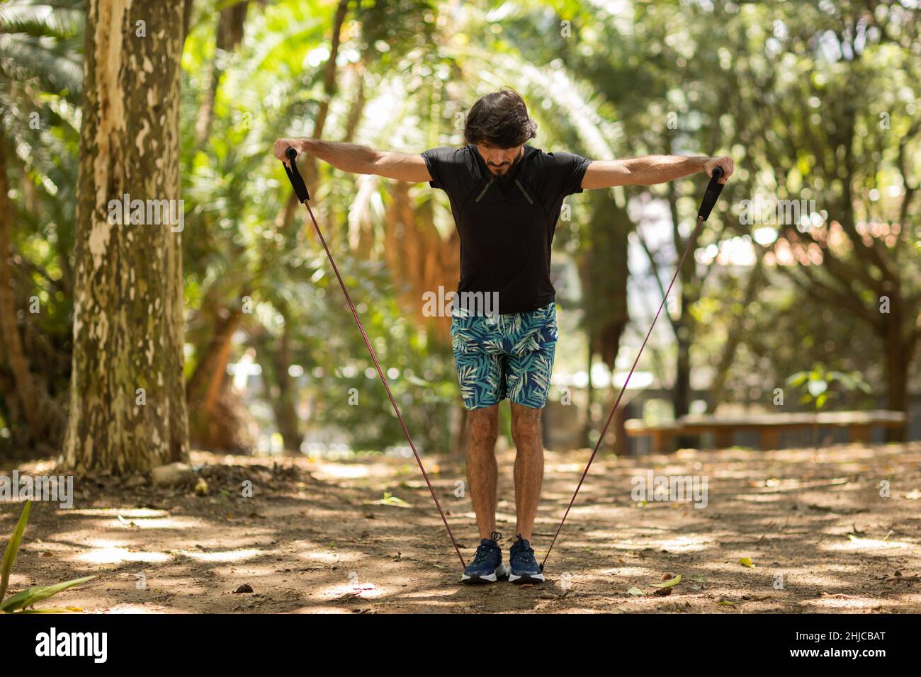 Strong man guy working out with elastic rubber bands at a park outdoors ...