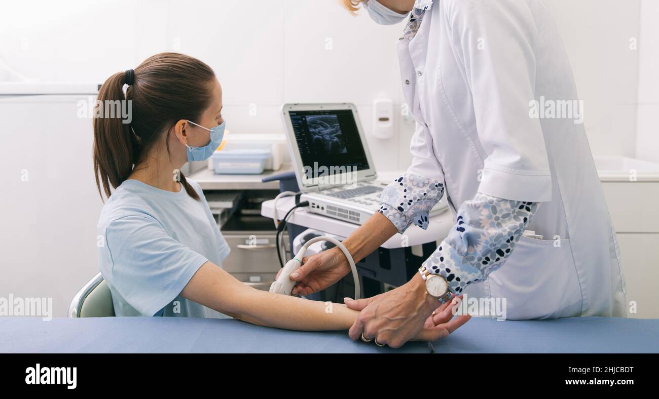 Doctor doing the ultrasound on the hand close up. Doctor demonstrates ...