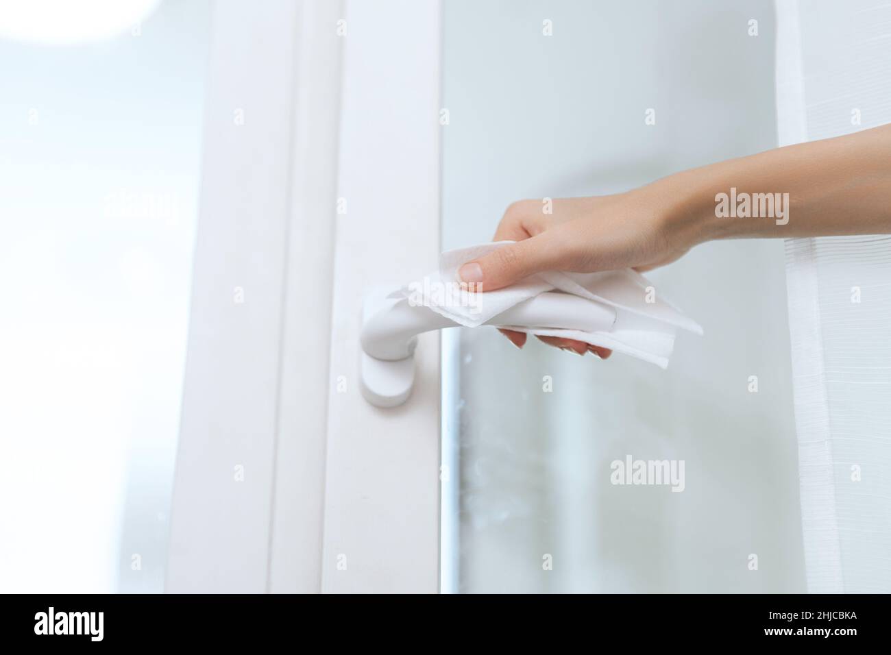 Cleaning door handles with an antiseptic wet wipe and gloves. Woman ...