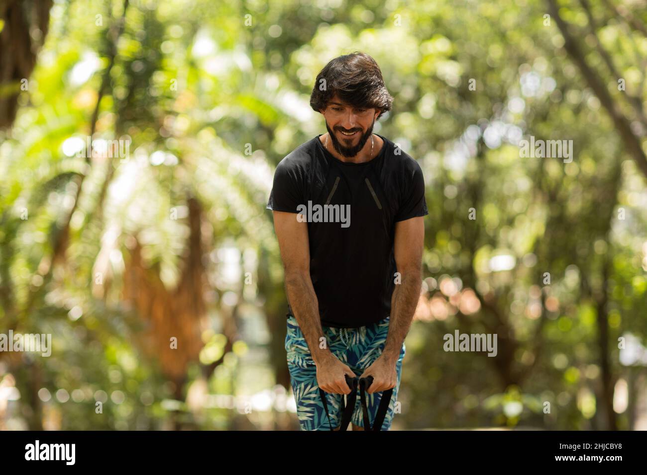 Strong man guy working out with elastic rubber bands at a park outdoors ...