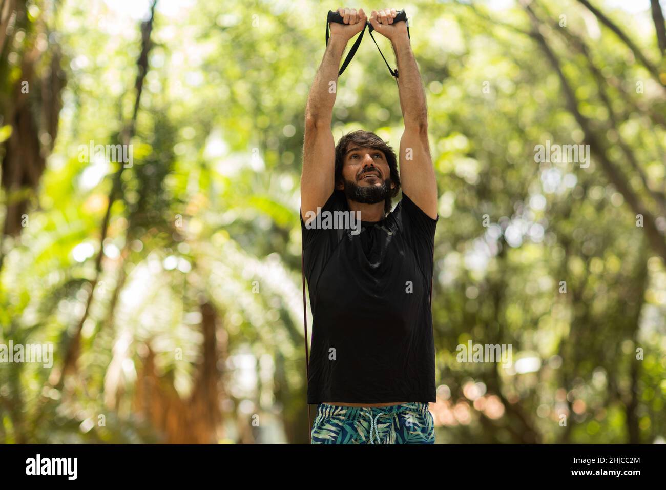Strong man guy working out with elastic rubber bands at a park outdoors ...