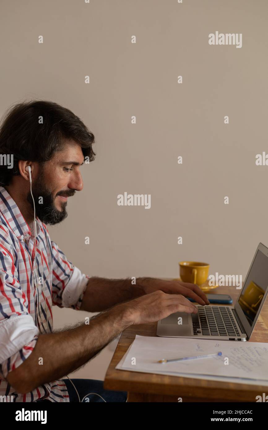 Young business man working at home with laptop on a brown arm chair ...