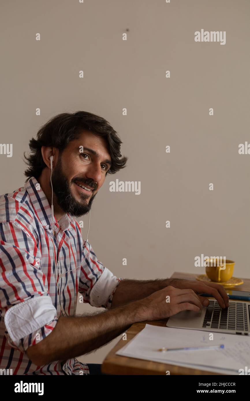 Young business man working at home with laptop on a brown arm chair ...