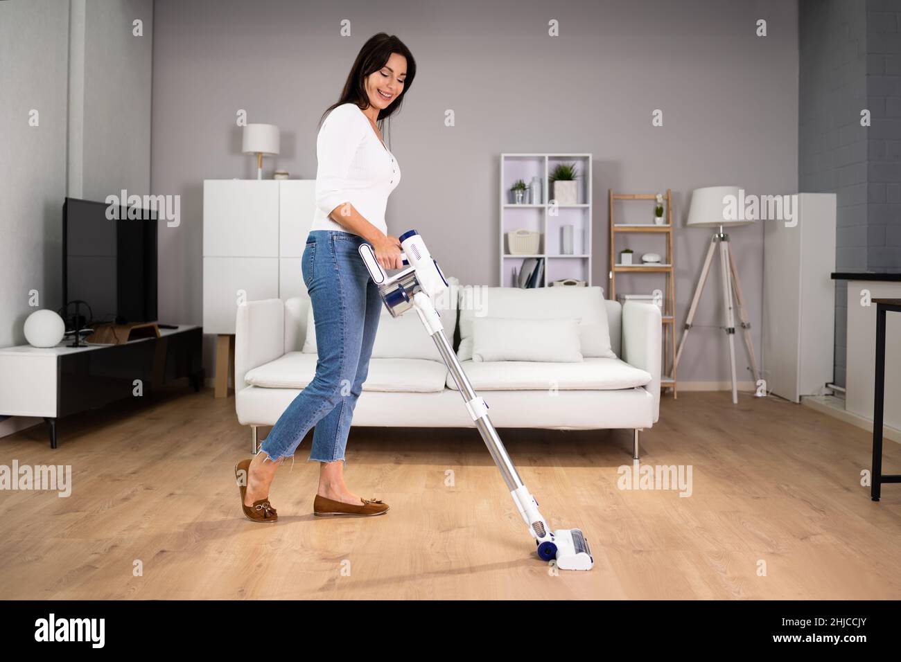 Young Maid Cleaning Floor With Handheld Vacuum Cleaner Stock Photo - Alamy