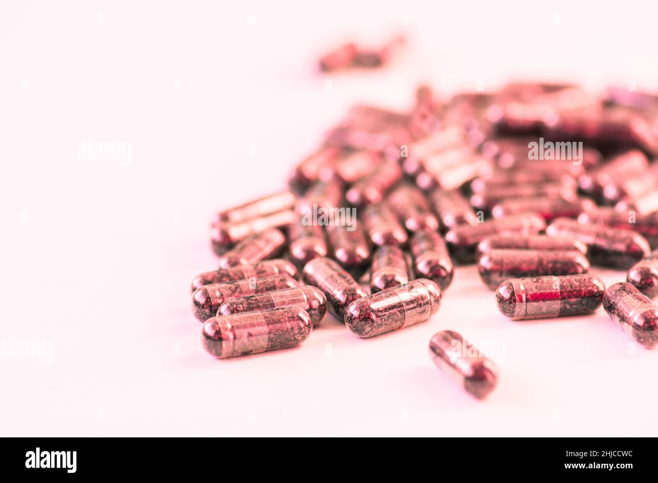 Black capsules on a pink background, Conceptual image of depression or ...