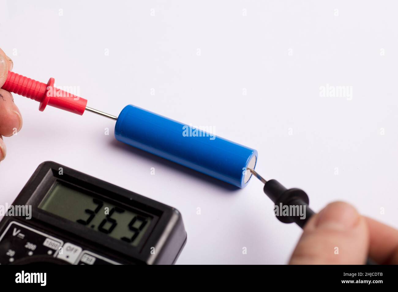 18650 blue battery, multimeter red and black poles in the hands of man ...