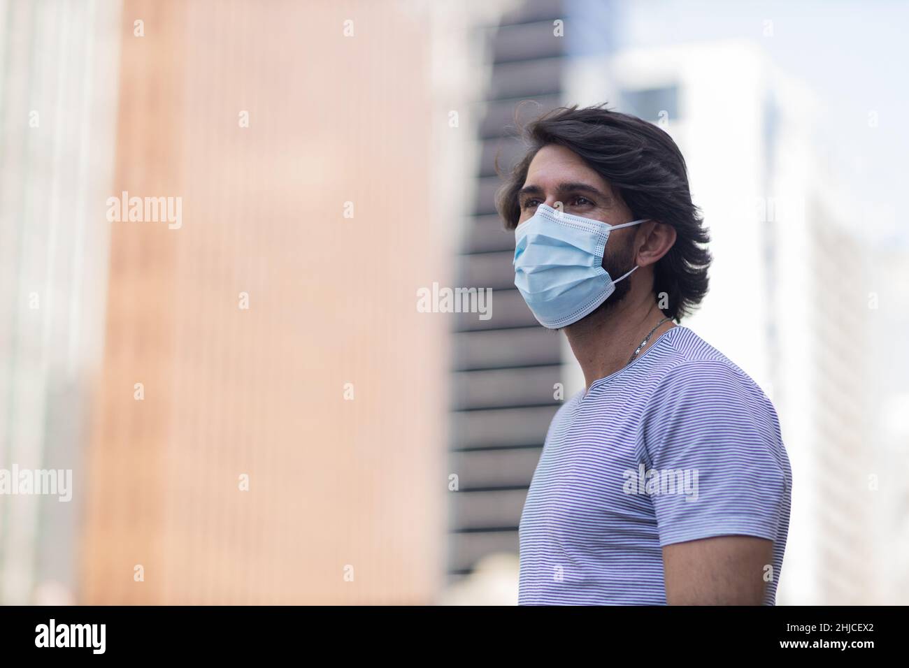 Portrait of a handsome man wearing a medical protective mask on his face on a big city street on ...