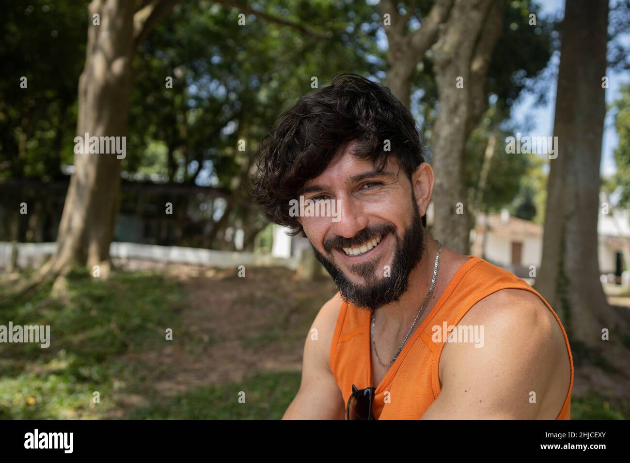 Portrait of smiling young man at a park on a beautiful sunny day. Green ...