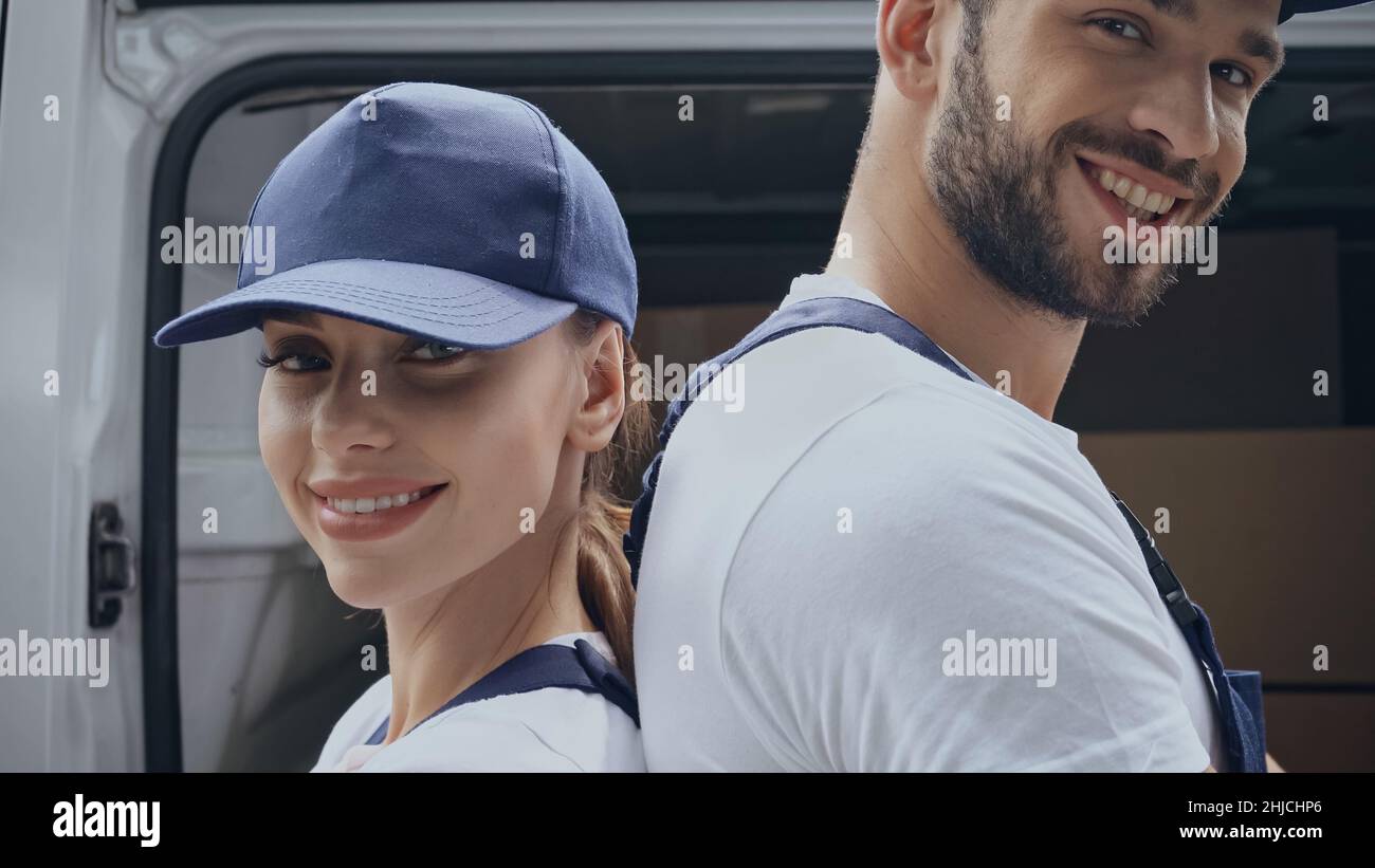 Positive couriers looking at camera near car outdoors Stock Photo - Alamy