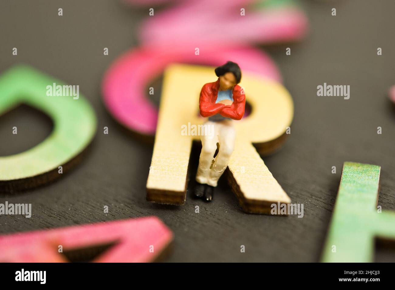 figurine of a woman sitting on letters Stock Photo - Alamy