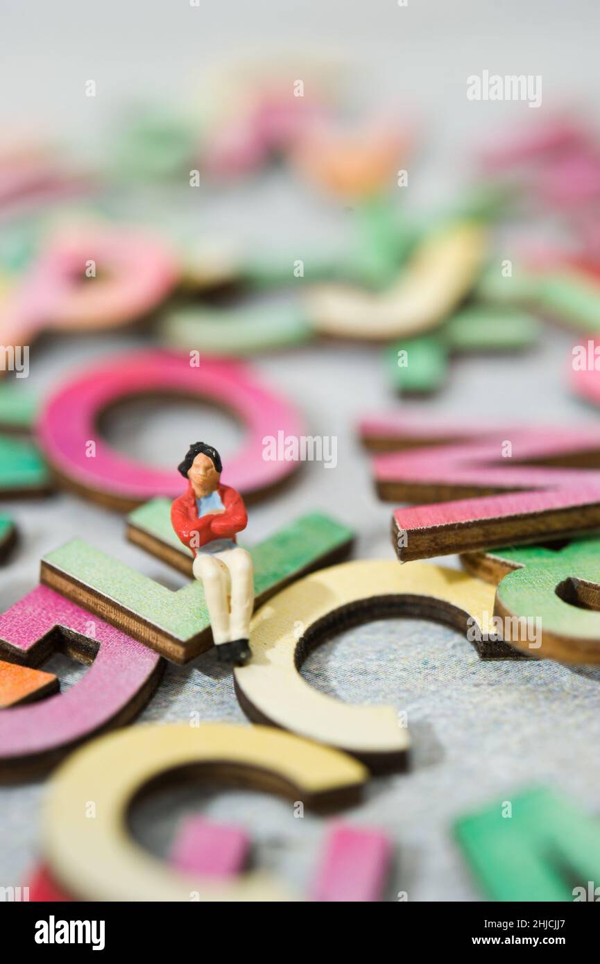 figurine of a woman sitting on letters Stock Photo - Alamy