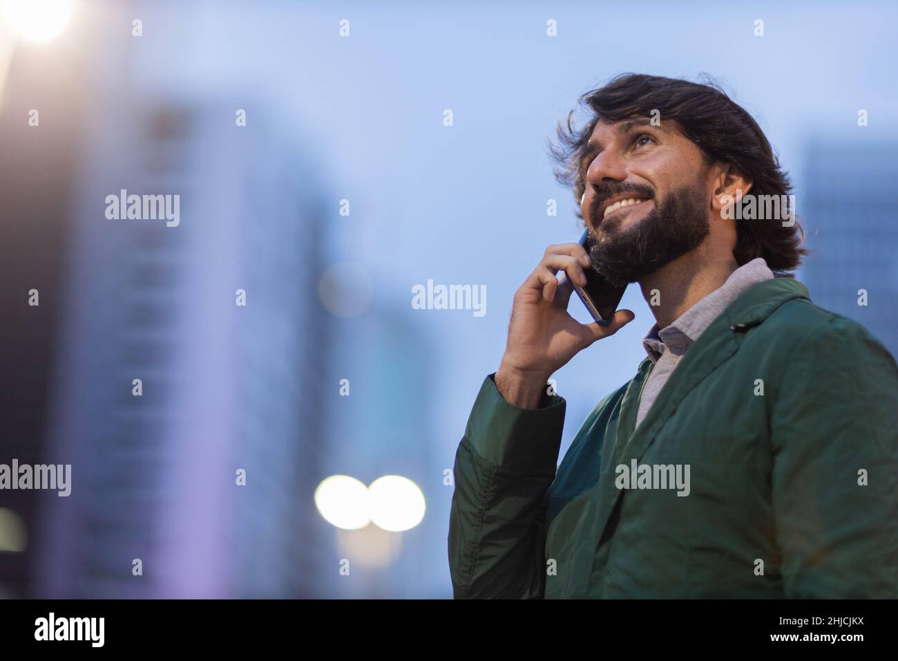 View of young man using a smartphone at night time with city view ...