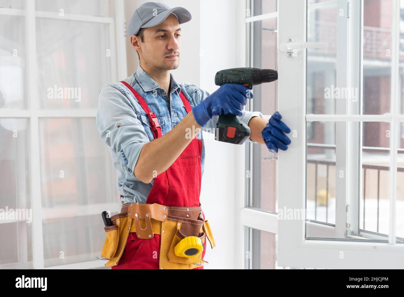 handsome young man installing bay window in a new house construction ...