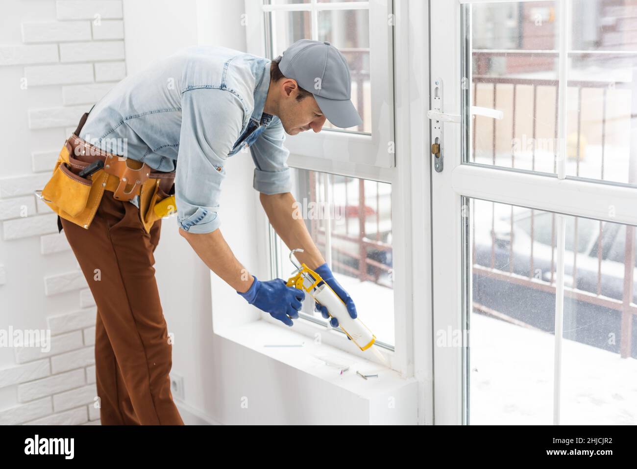 handsome young man installing bay window in a new house construction ...